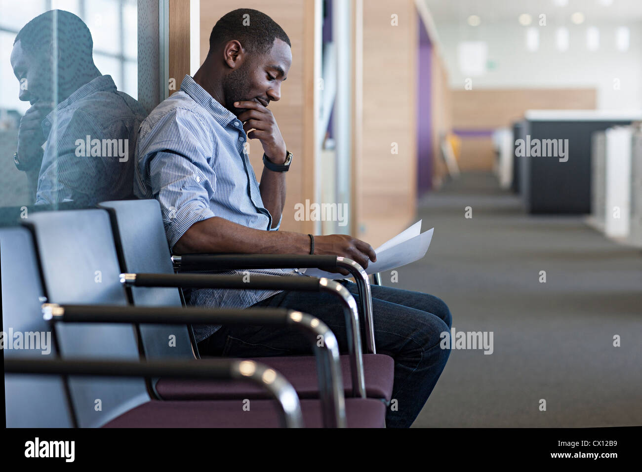 Man sitting on chair reading document Stock Photo - Alamy