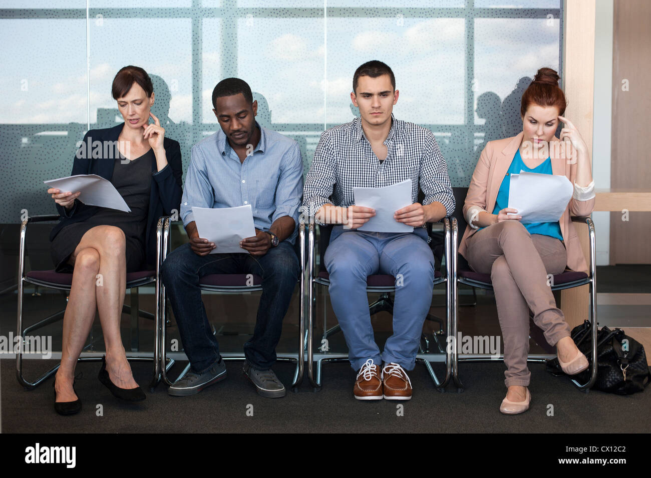 Four people sitting on chairs with documents Stock Photo - Alamy