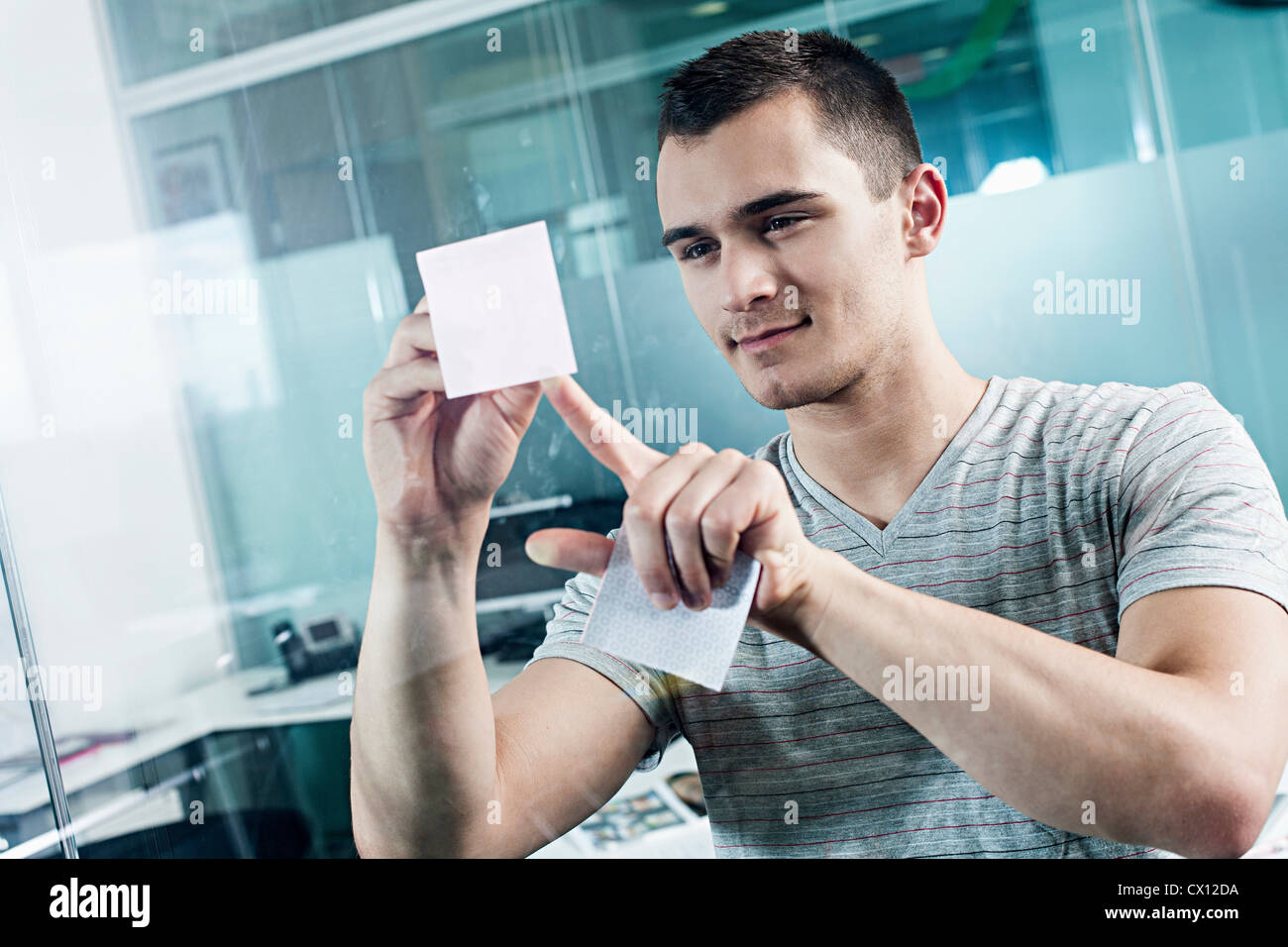 Man sticking adhesive note to window Stock Photo - Alamy