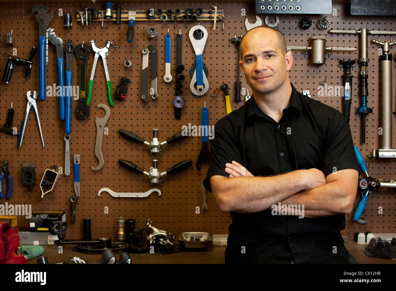 Man in front of wall of tools in workshop Stock Photo - Alamy