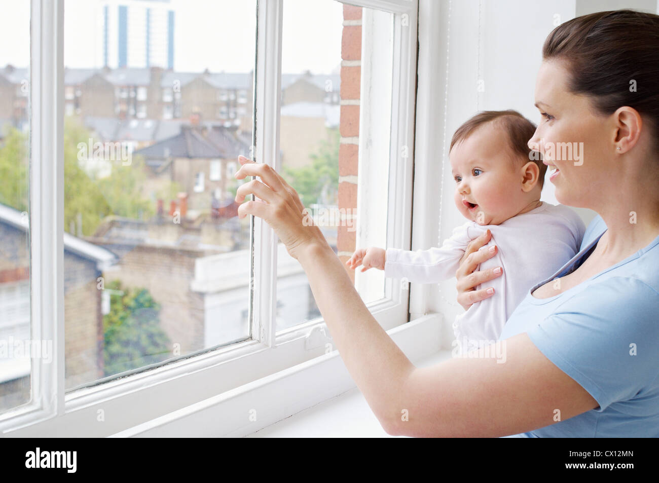 Mother and baby looking through a window Stock Photo - Alamy