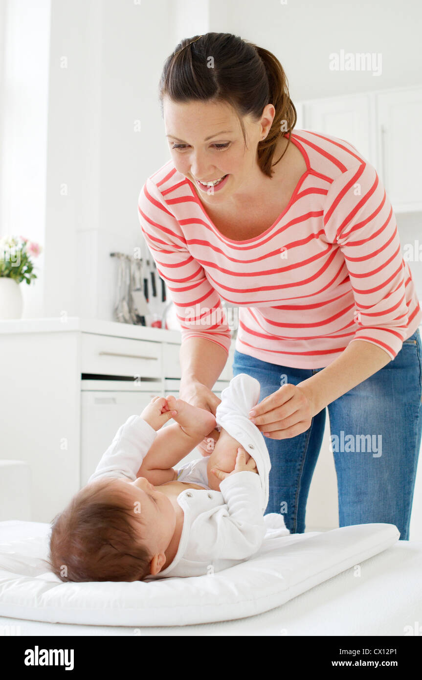 Mother changing baby daughter Stock Photo - Alamy
