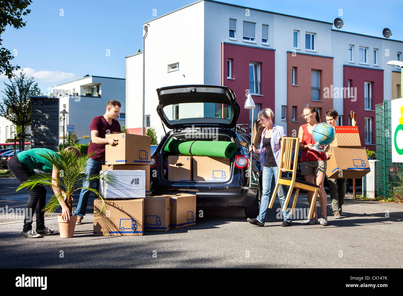 Moving. Young people moving from one home into a new one. Carrying ...