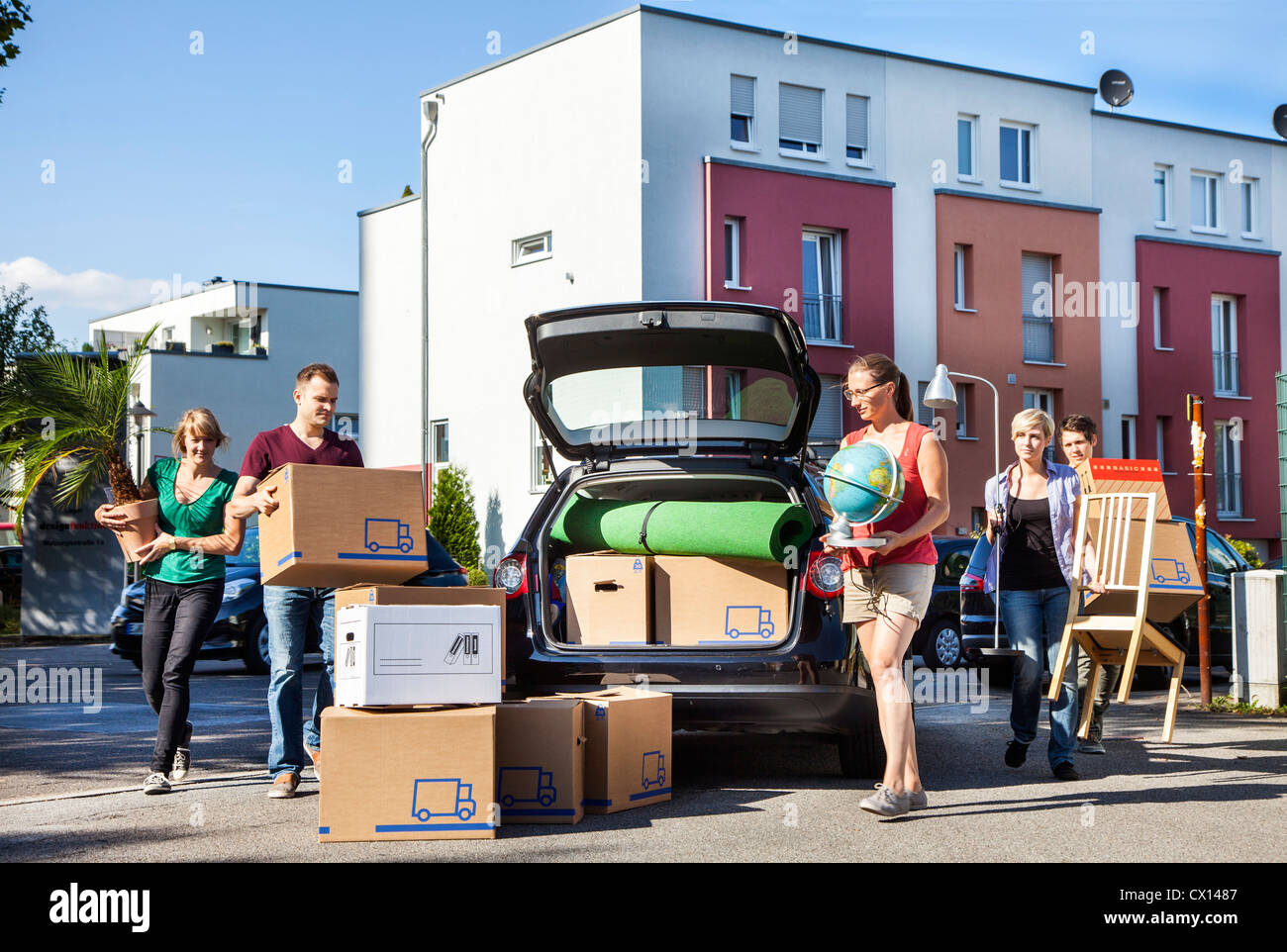 Moving. Young people moving from one home into a new one. Carrying ...
