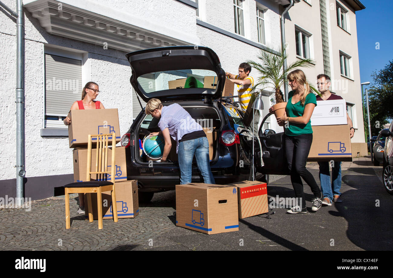 Moving. Young people moving from one home into a new one. Carrying ...