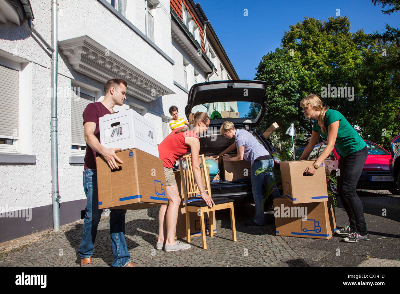 Moving. Young people moving from one home into a new one. Carrying ...