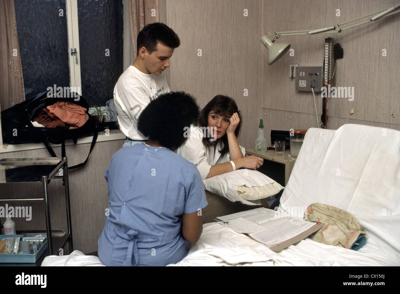 midwife and partner assisting a woman in labour labor in birthing room ...