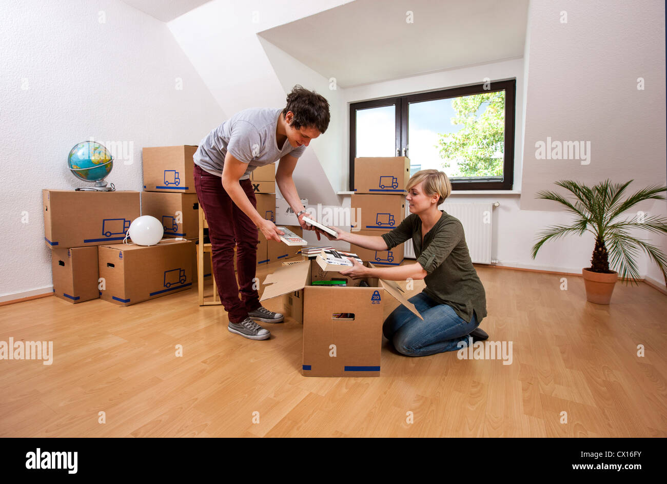 Young couple, just moved into a new apartment. Unpacking moving boxes ...