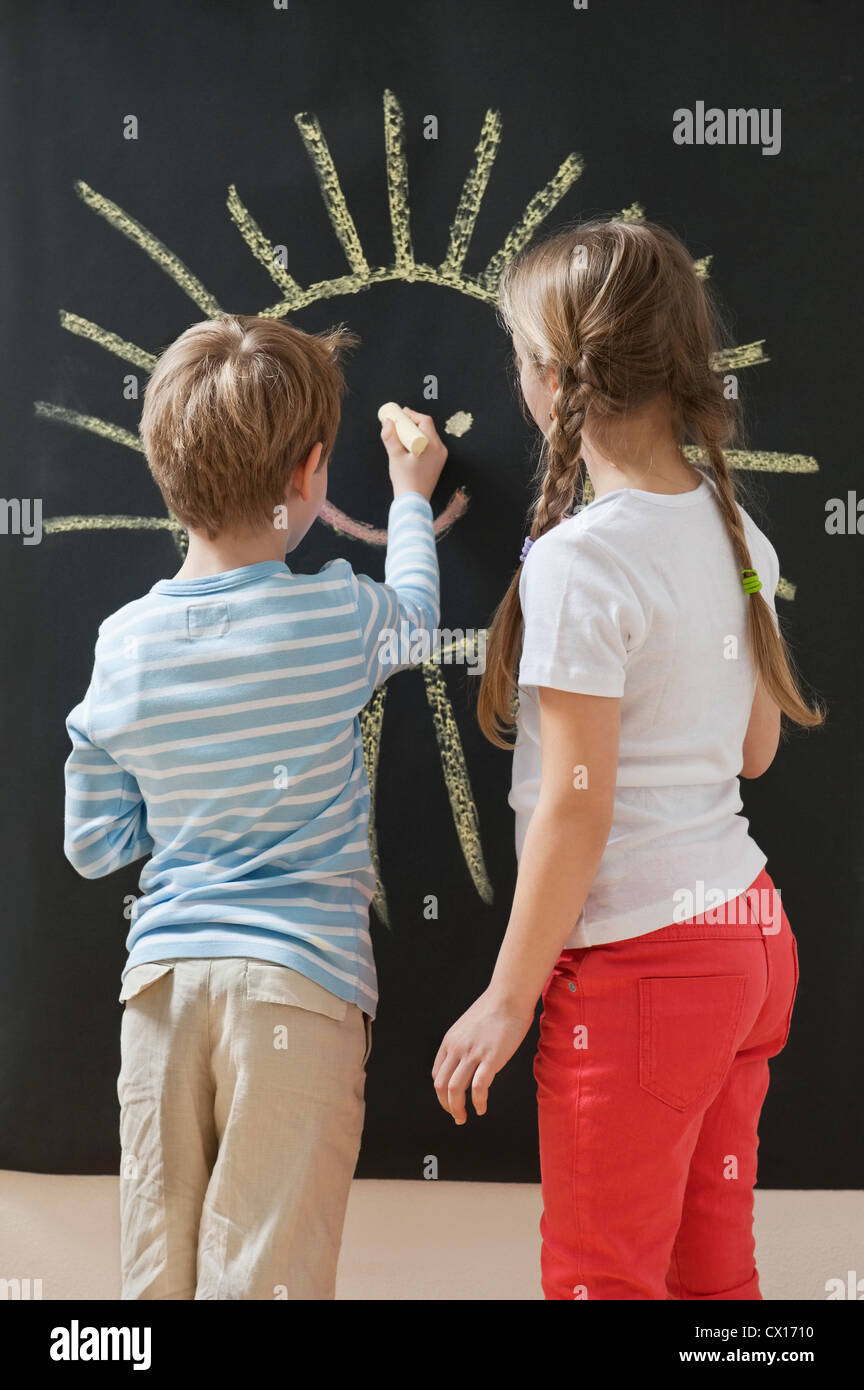 Back view of siblings drawing sun on blackboard Stock Photo - Alamy