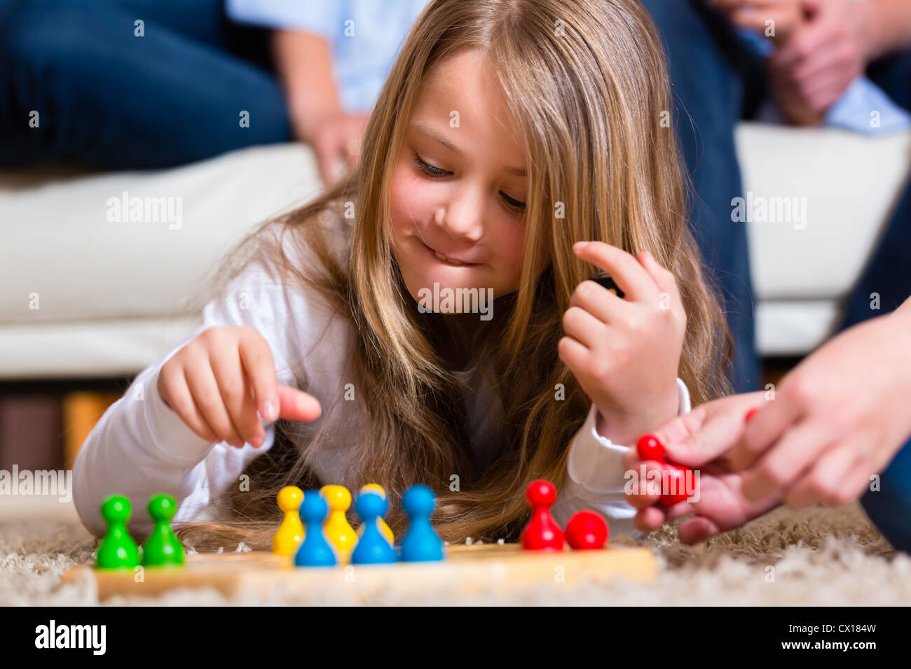 Family playing board game ludo at home on the floor, close up on child ...