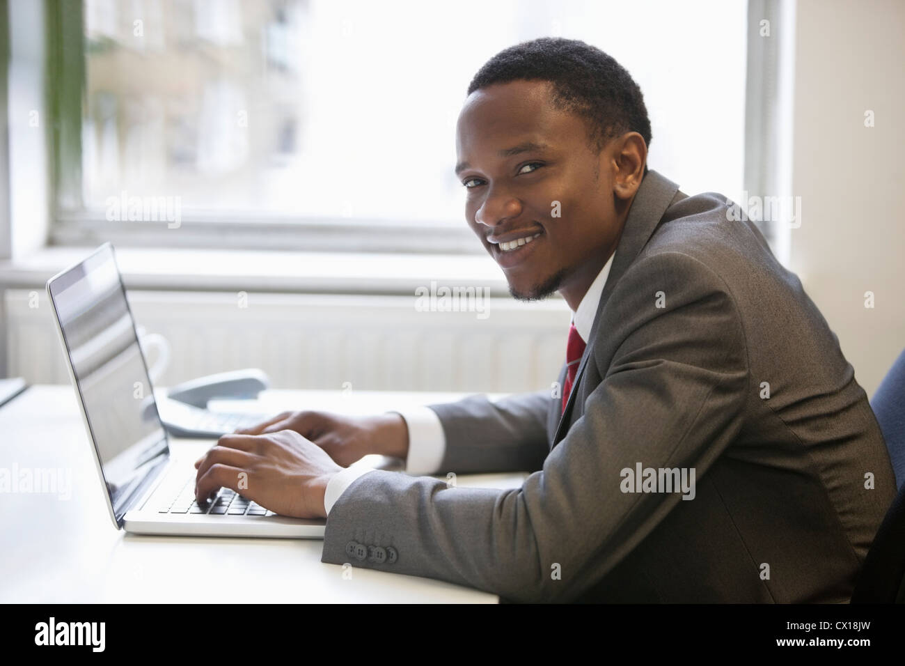 Portrait of happy African American businessman using laptop at office desk Stock Photo - Alamy