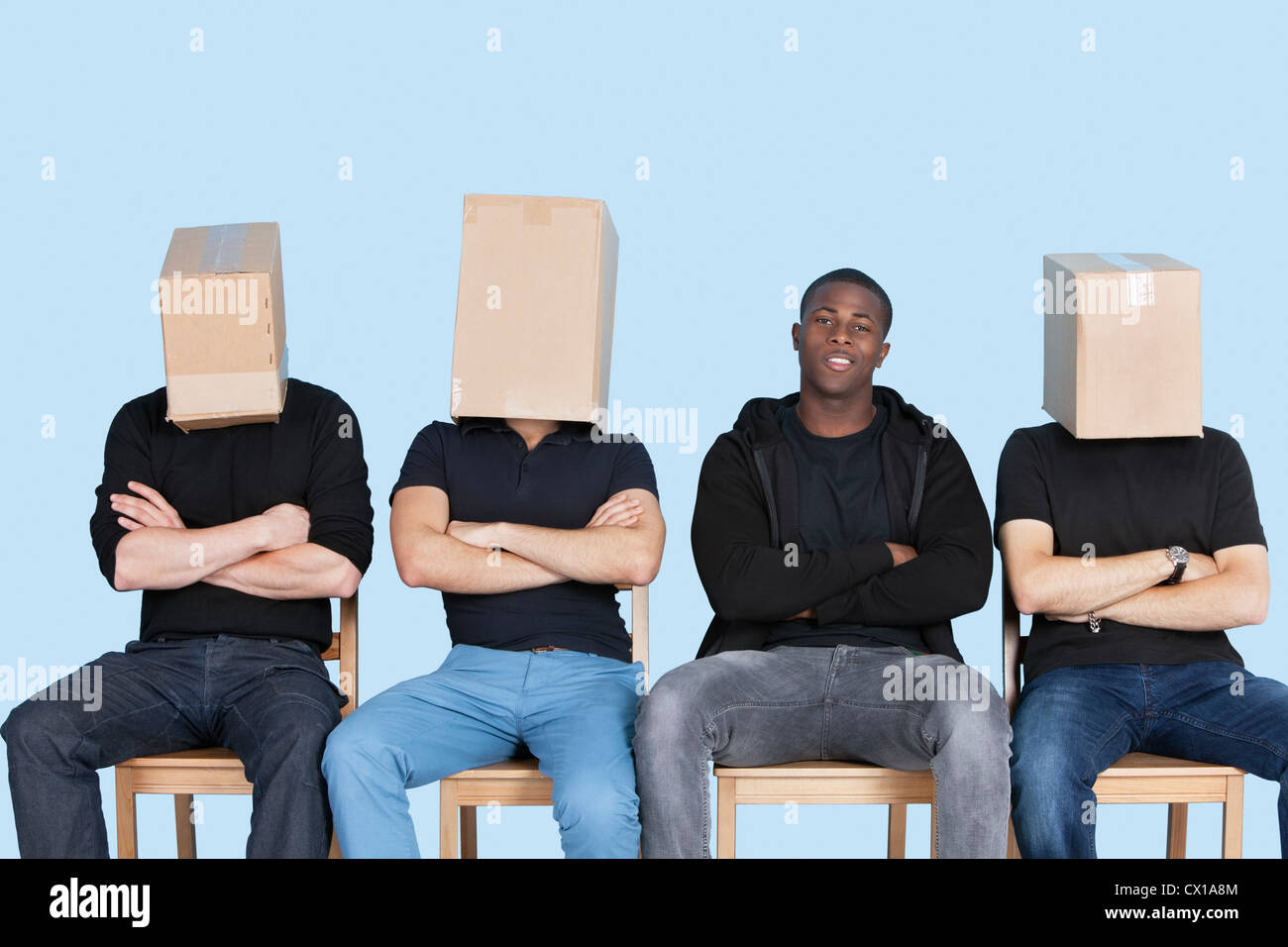 Man with friends faces covered with cardboard boxes as they sit on ...