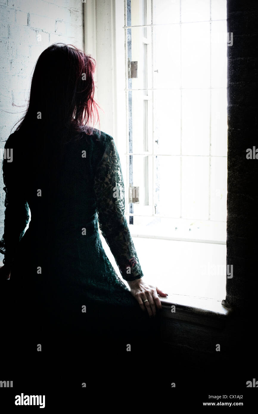 Woman gazing through window Stock Photo - Alamy