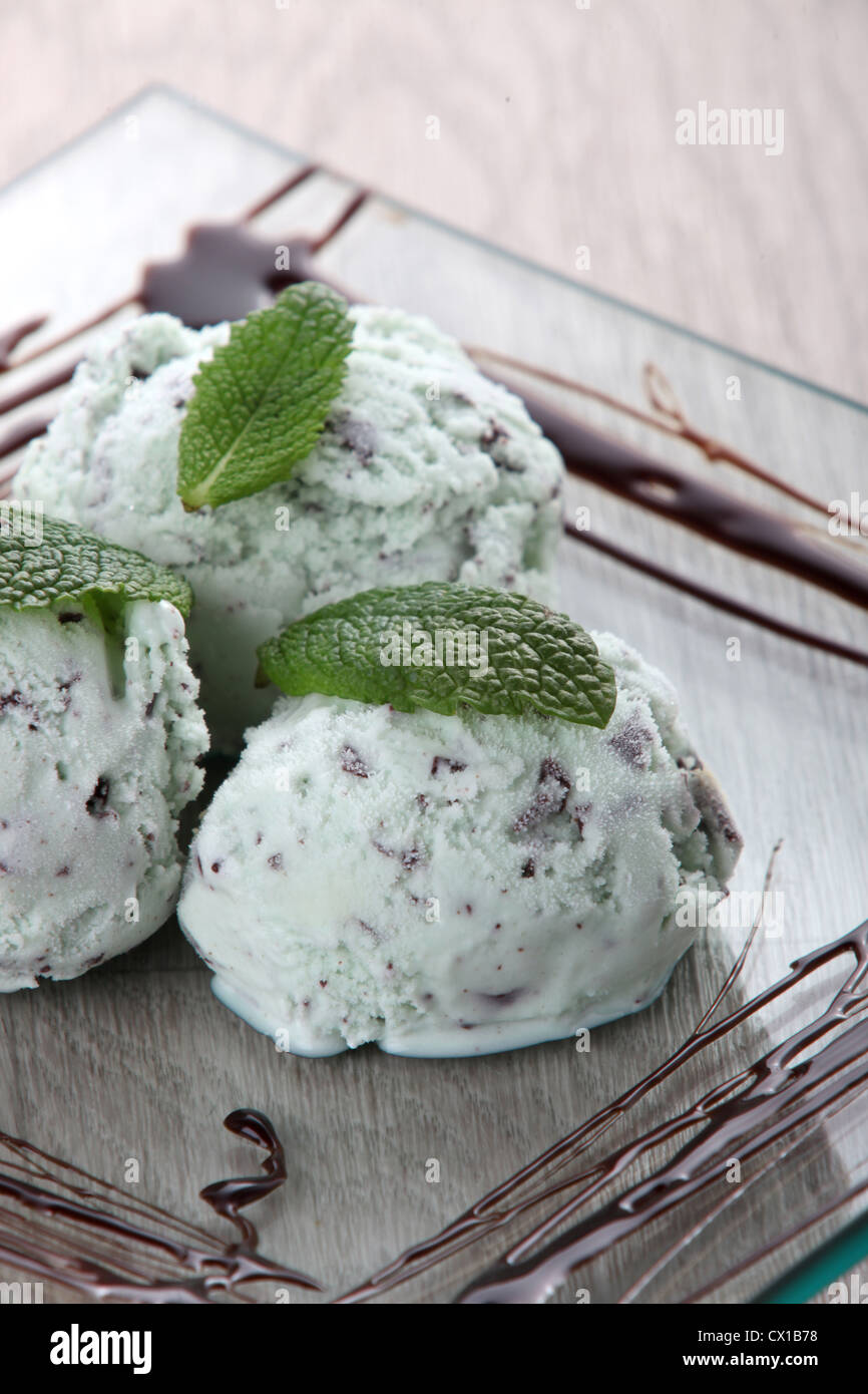 Three balls of mint chocolate chip ice cream on a square glass platter ...