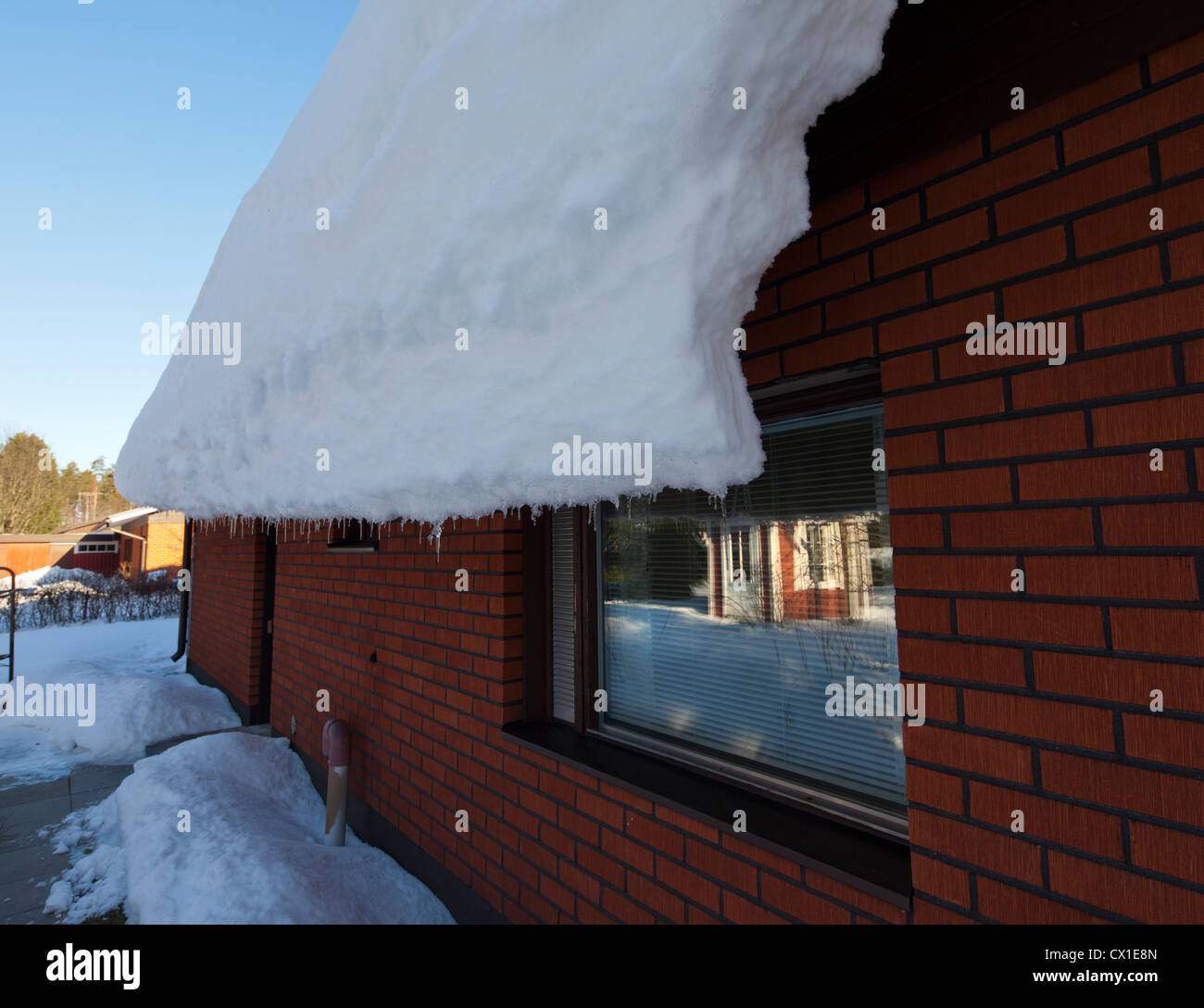 Snow and ice sliding from the roof and hanging over house roof eaves ...