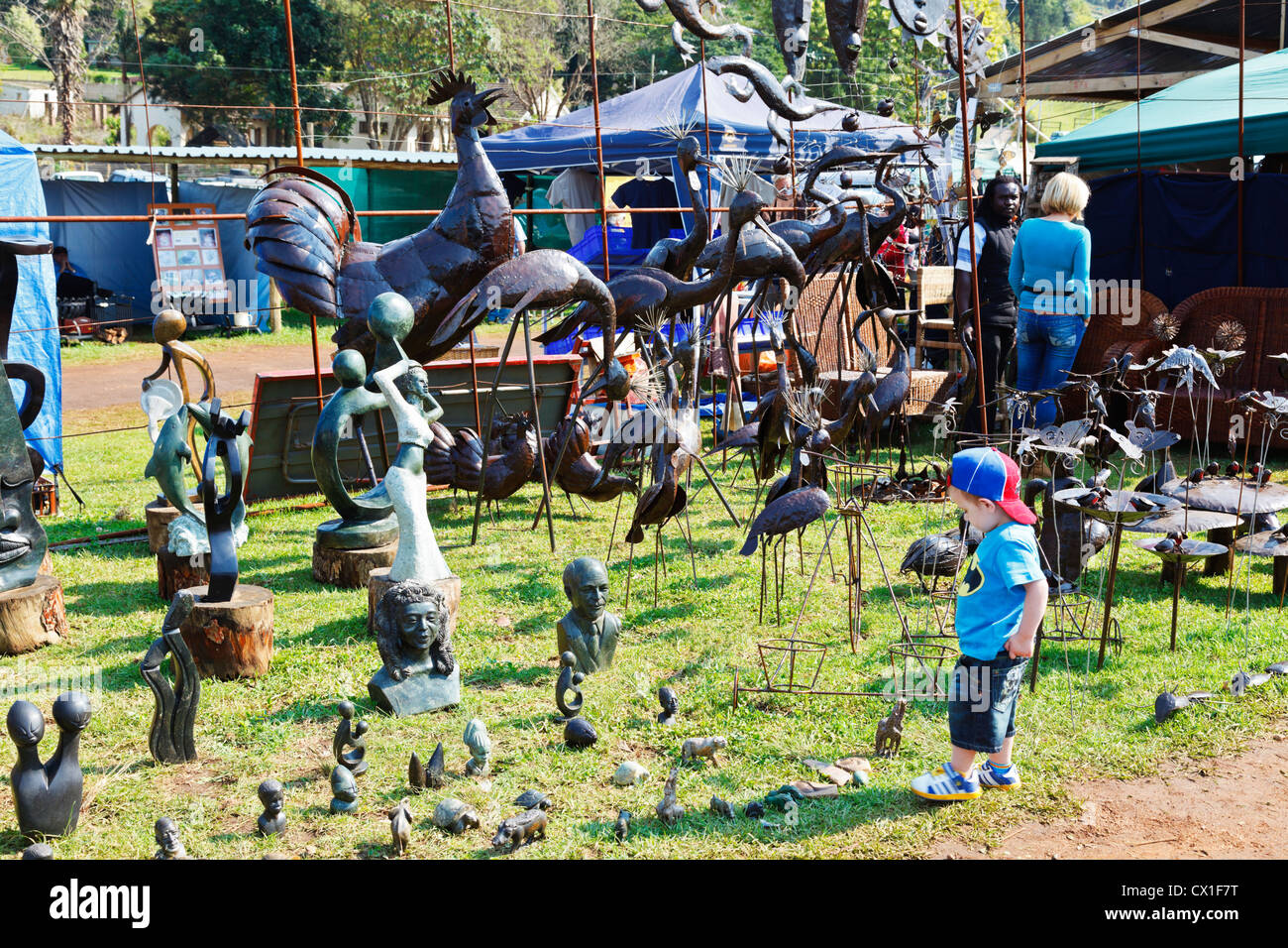 A young boy looks at a display of soapstone carvings and metal ...