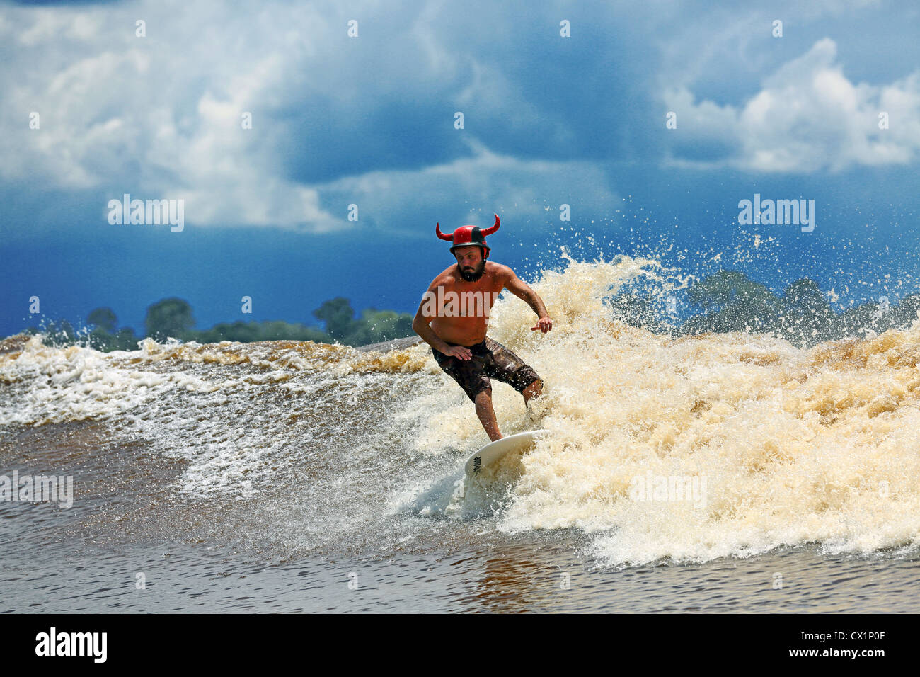 A man surfs a short surfboard on a river tidal bore wave in Sumatra ...