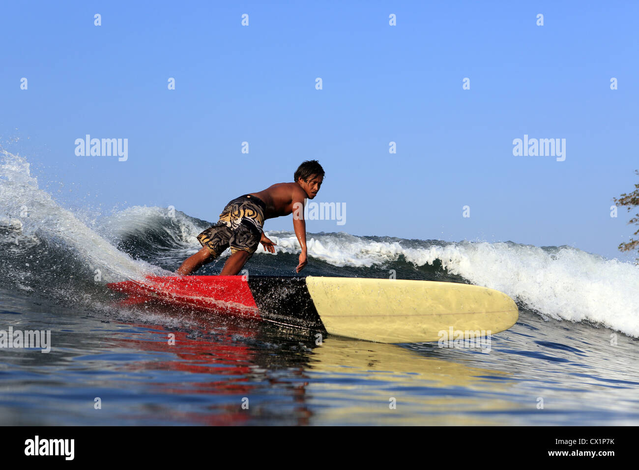 Local surfer surfing the point break wave on a longboard at Batu Karas ...