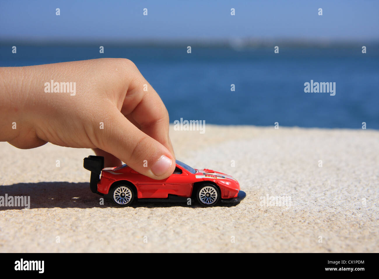 Close-up of a child hand playing with a red car Stock Photo - Alamy