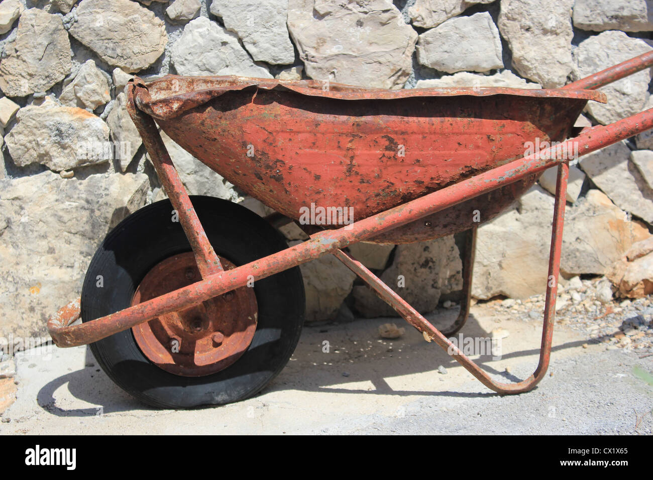 Thoroughly used up wheelbarrow on a stone wall background Stock Photo ...