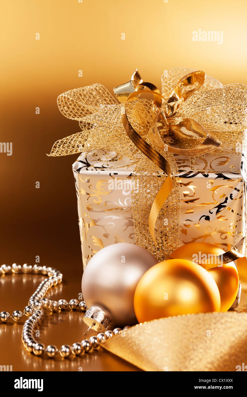 christmas present with christmas balls and a chain on golden background ...