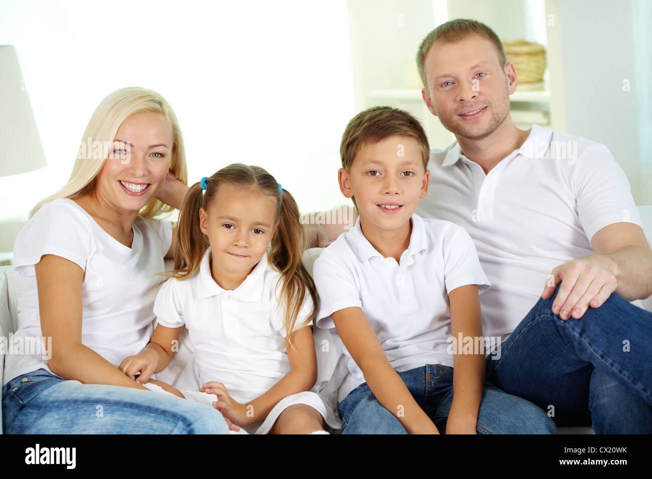 Portrait of happy family with two children sitting at home Stock Photo ...