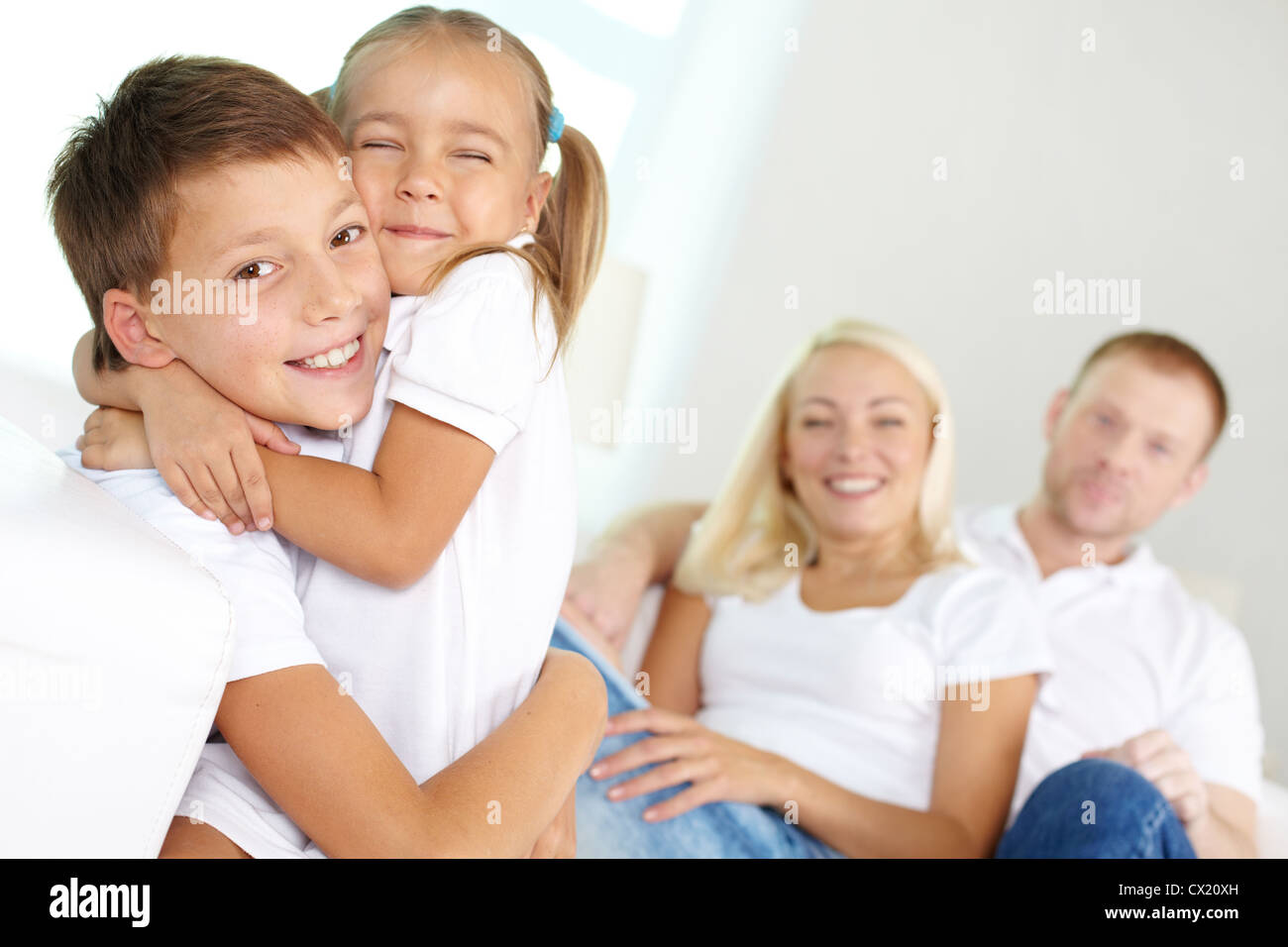 Portrait of happy children embracing with parents sitting behind Stock ...