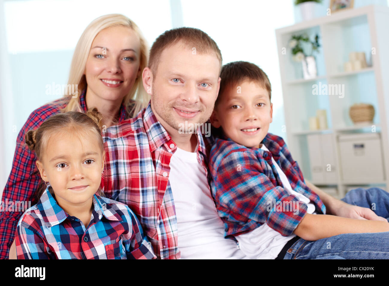 Portrait of happy family with two children looking at camera at home ...