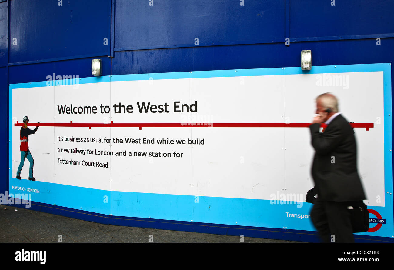 Pedestrian in London streets, passing a large poster Stock Photo - Alamy