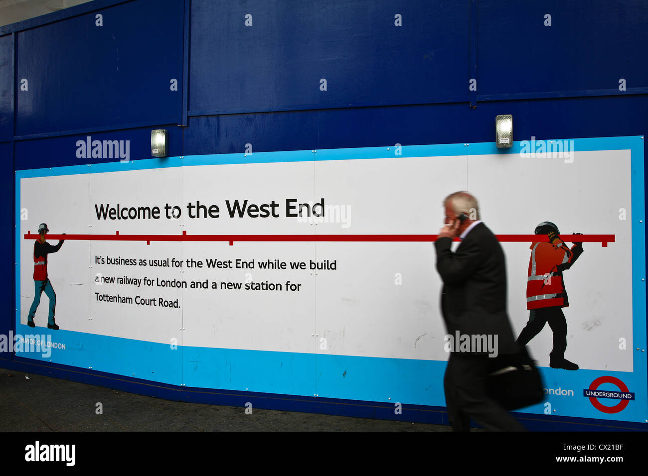 Pedestrian in London streets, passing a large poster Stock Photo - Alamy