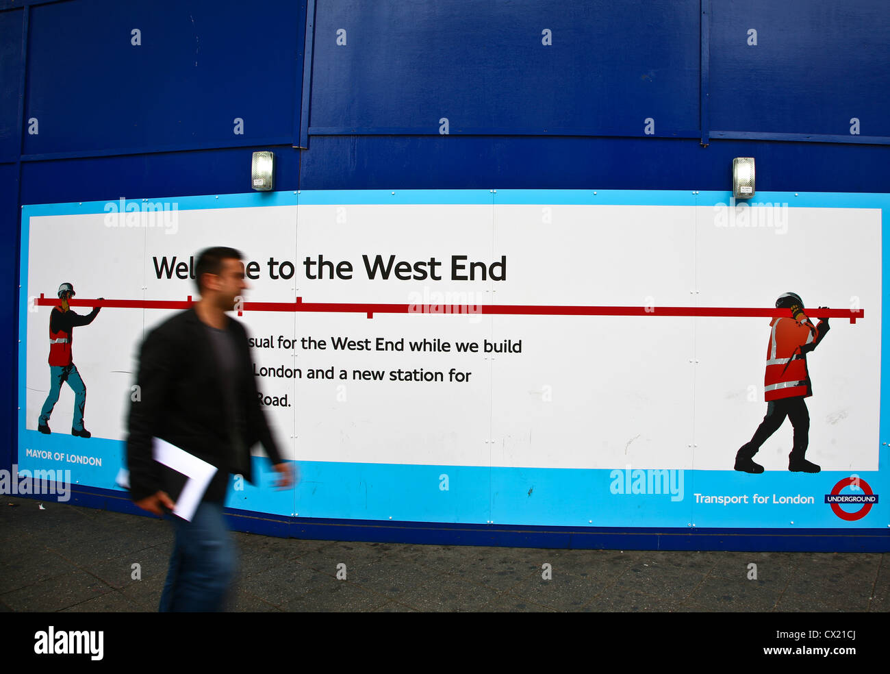 Pedestrian in London streets, passing a large poster Stock Photo - Alamy