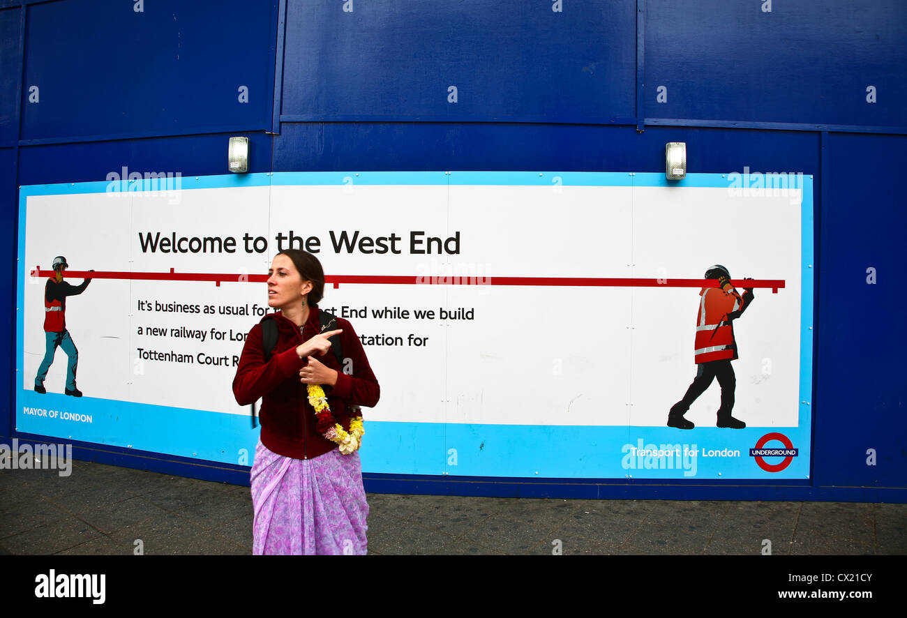 Pedestrian in London streets, passing a large poster Stock Photo - Alamy