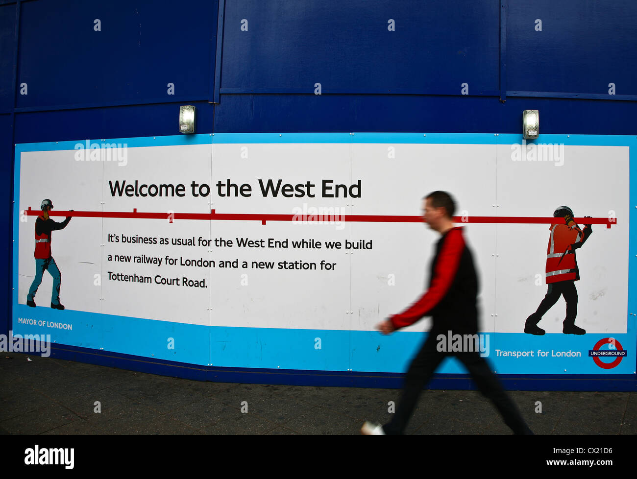 Pedestrian in London streets, passing a large poster Stock Photo - Alamy