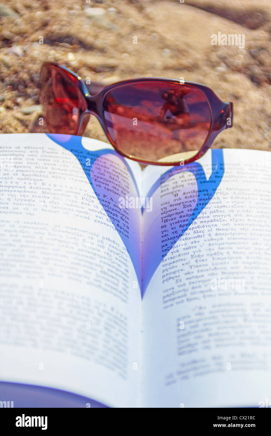 Sunglasses left on a book with the sun forming a heart on the pages ...
