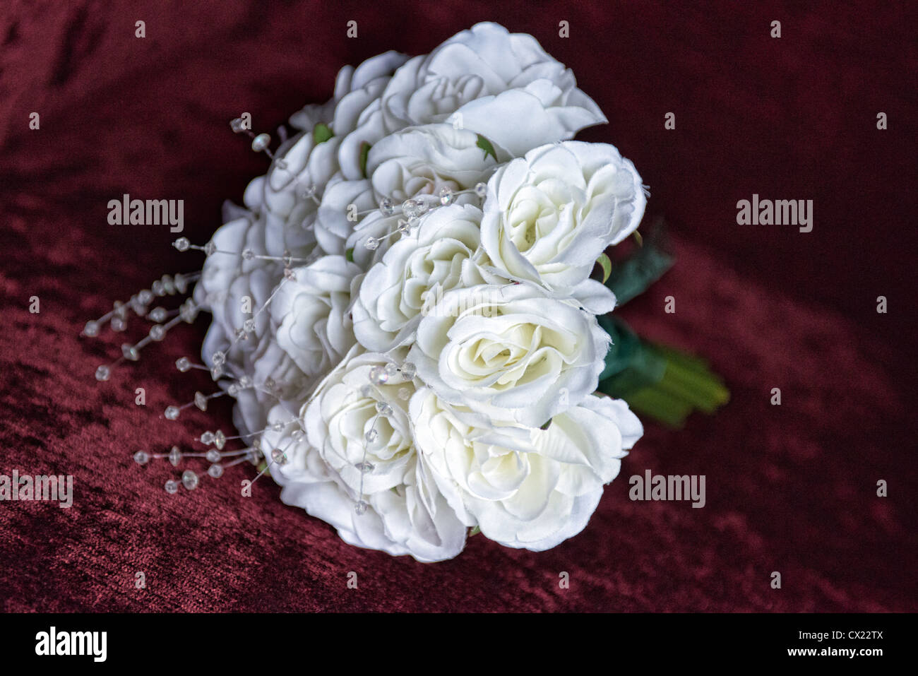 A posie of white roses on a red velvet background Stock Photo - Alamy
