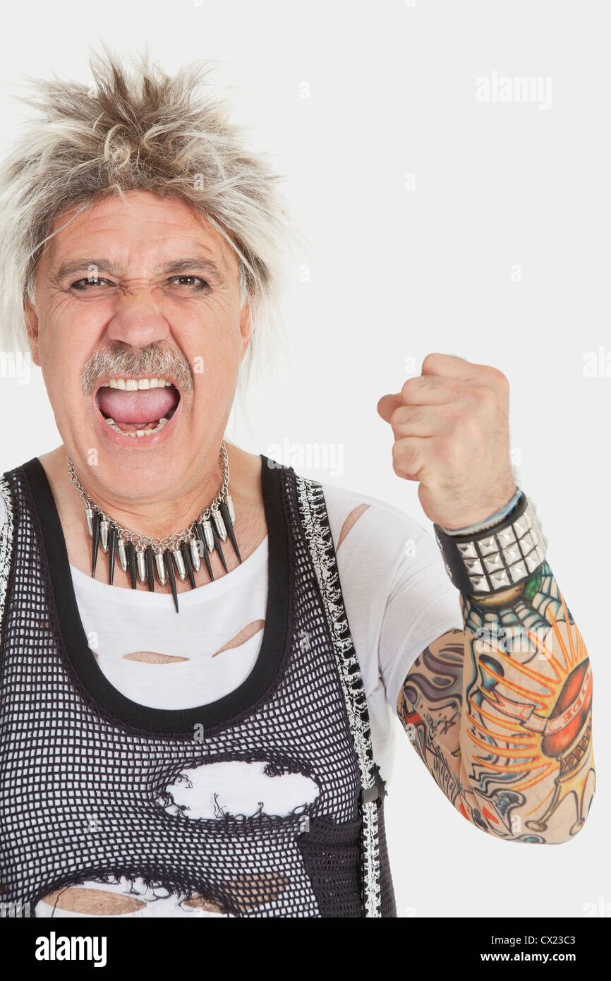 Portrait of senior male punk screaming with clenched fist over gray ...