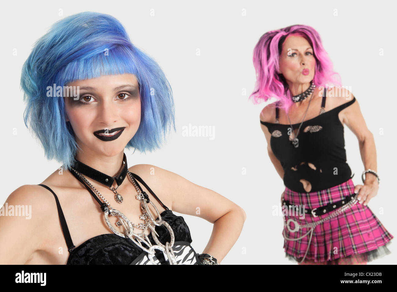 Portrait of happy young and senior female punks against gray background ...