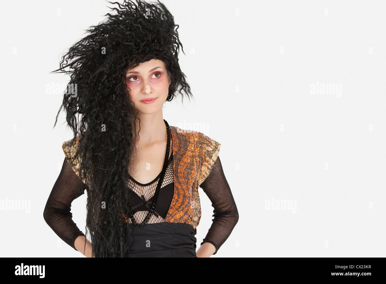 Beautiful young Goth woman with teased hair looking away over gray ...