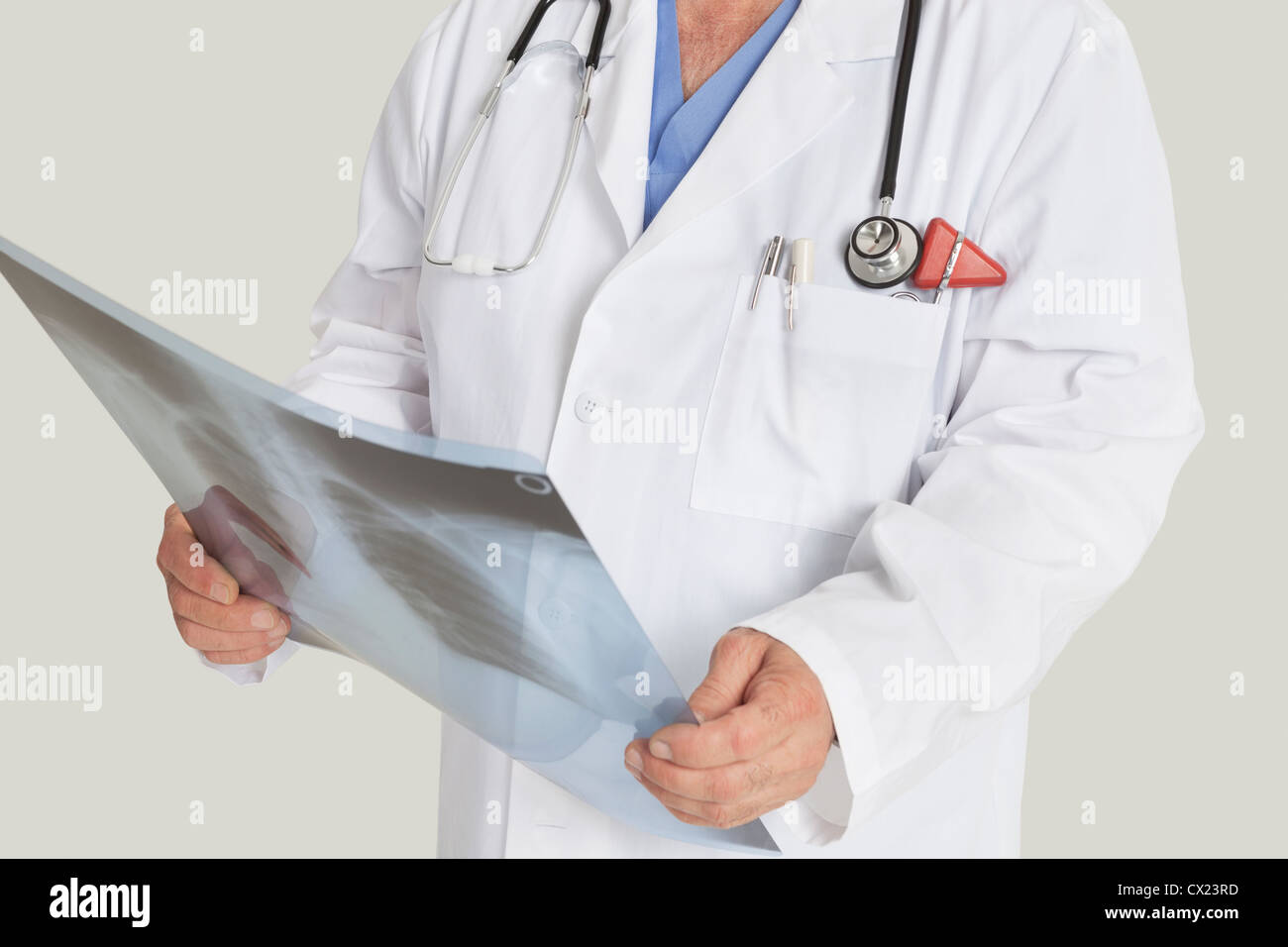 Midsection of male doctor with x-ray report over gray background Stock ...