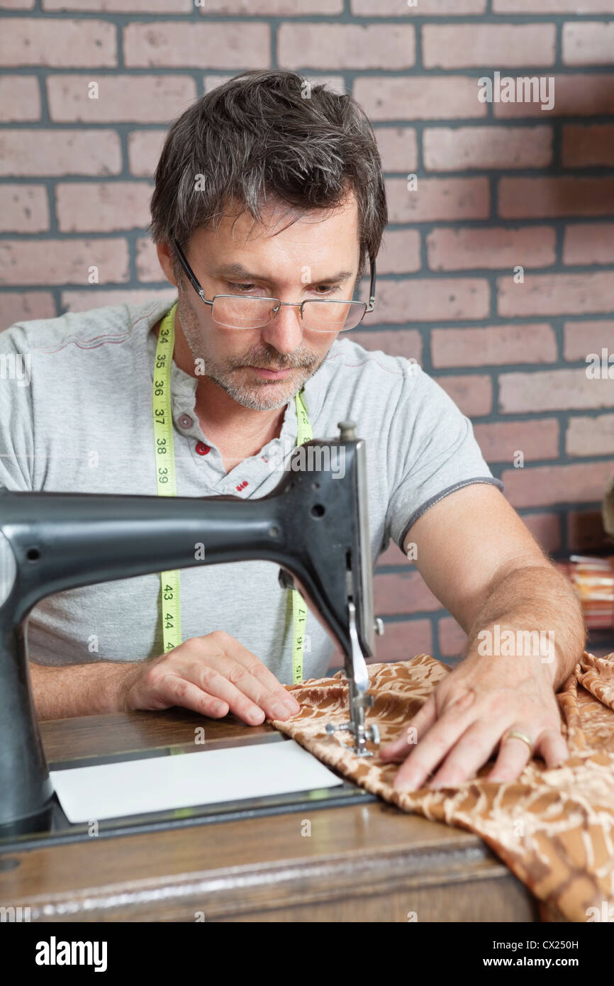 Mature male dressmaker stitching cloth on sewing machine Stock Photo ...