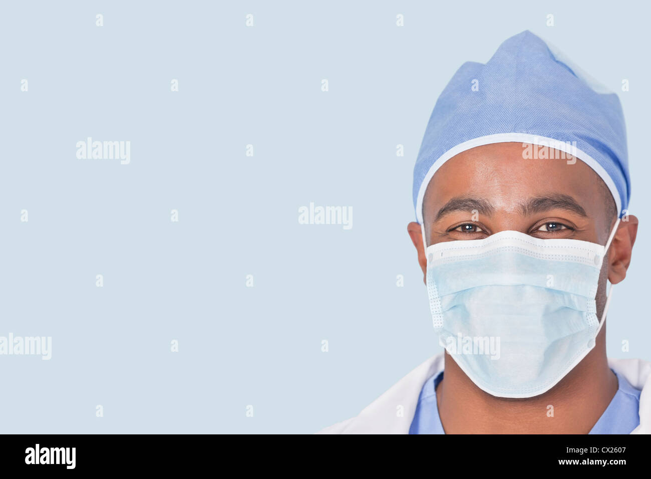 Close-up of a male doctor wearing facemask over light blue background ...