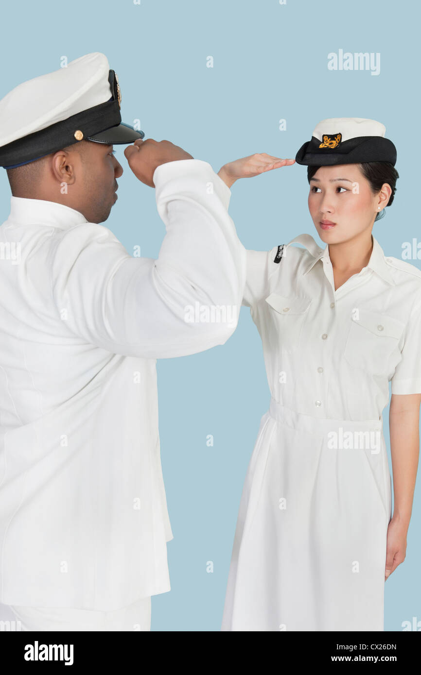 Multi-ethnic US Navy officers saluting each other over light blue ...