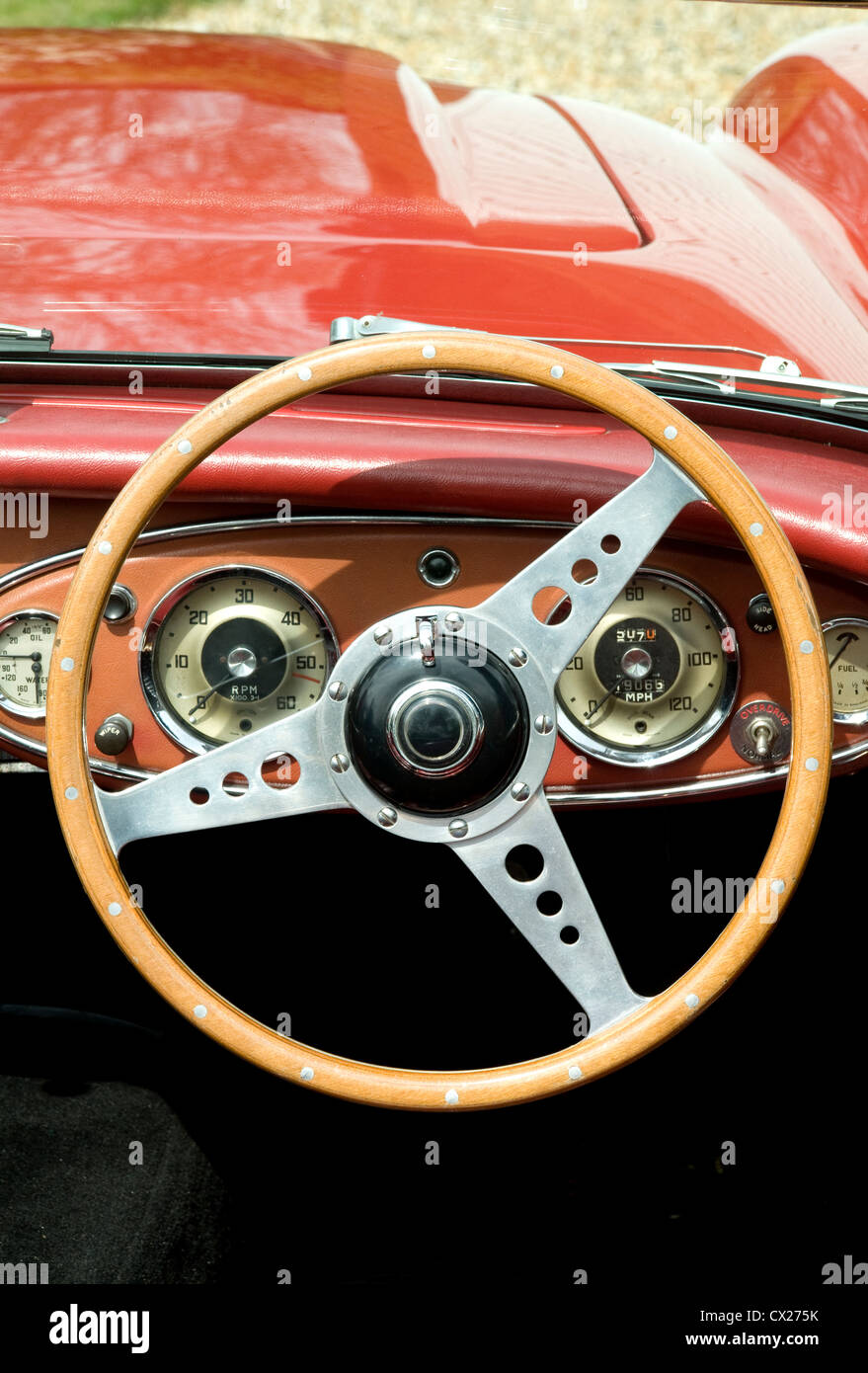 A wooden steering wheel, car fascia and interior of red vintage car ...