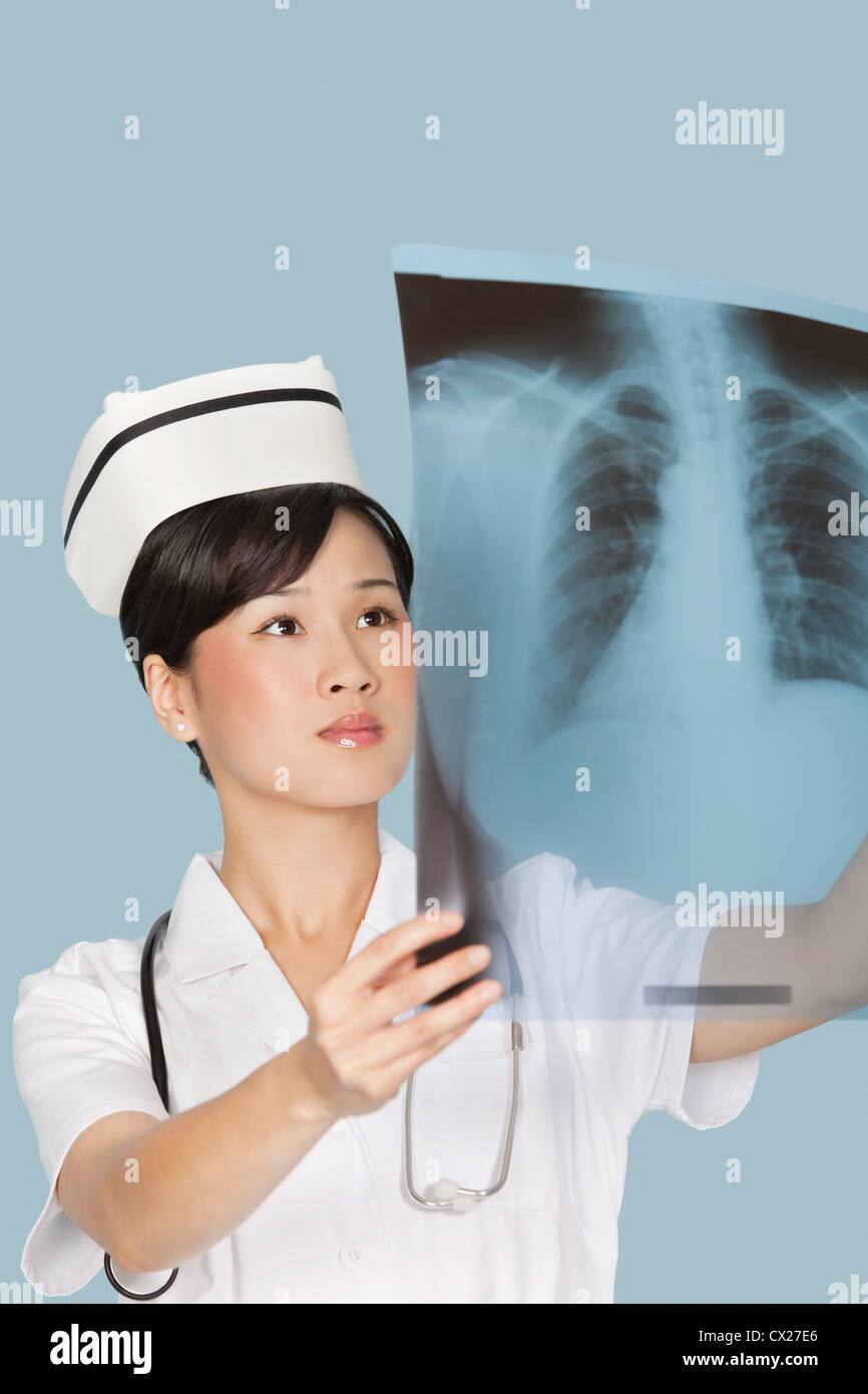 Female doctor analyzing x-ray report over light blue background Stock ...