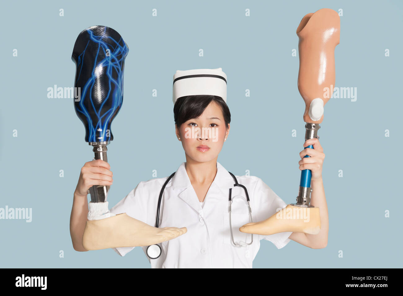 Female doctor holding up two artificial legs over light blue background ...