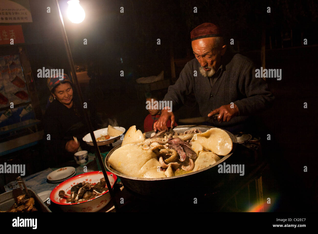 An Uighur man prepares offal at a food stall in Turpan, Xinjiang, China ...