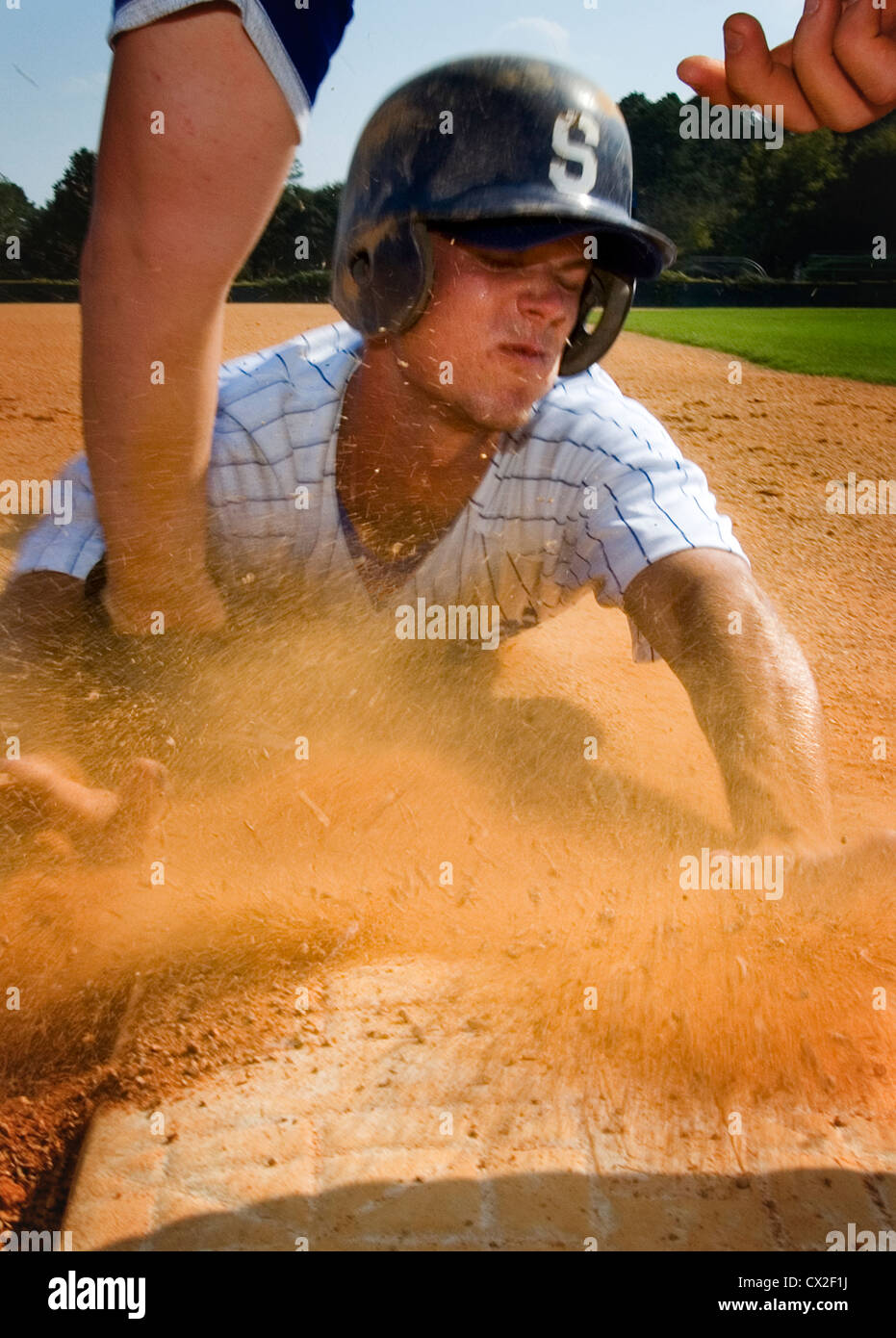 A helmet wearing college baseball player slides into third base on a ...