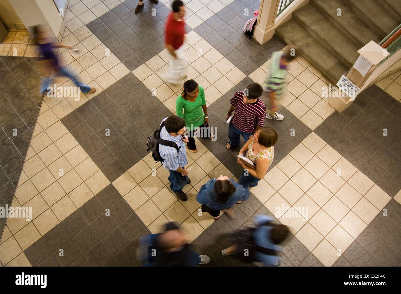 A group of college students meet to talk between classes as others walk ...