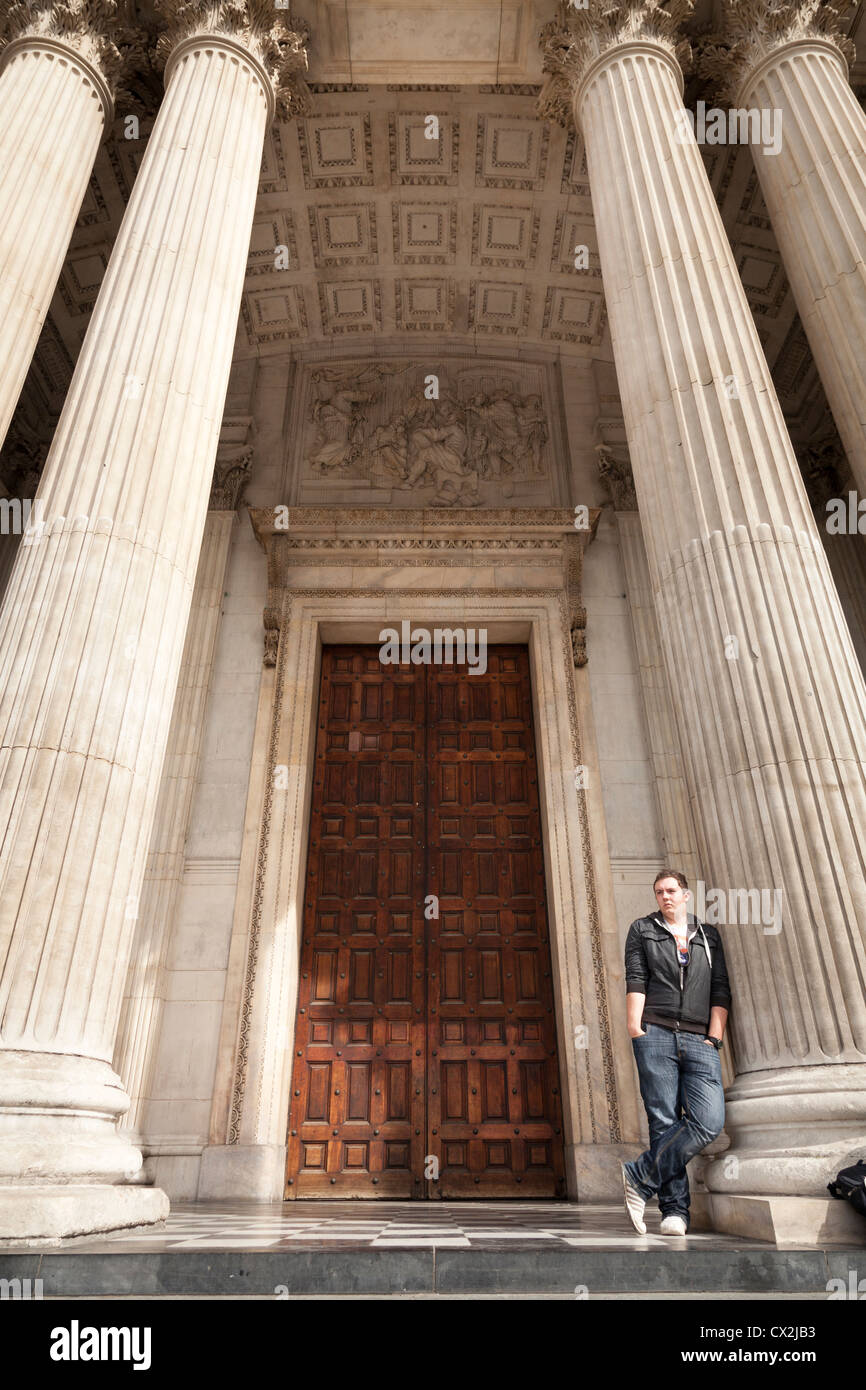 man leaning against one of the columns at the entrance to Saint Pauls ...