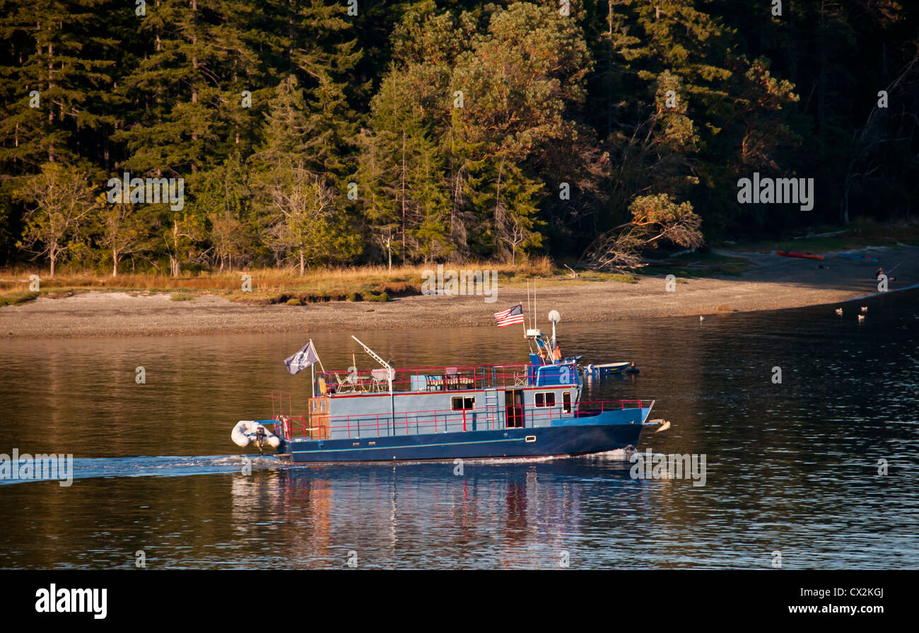 Puget Sound, Colorful Houseboat crusing near the shoreline of Hope ...